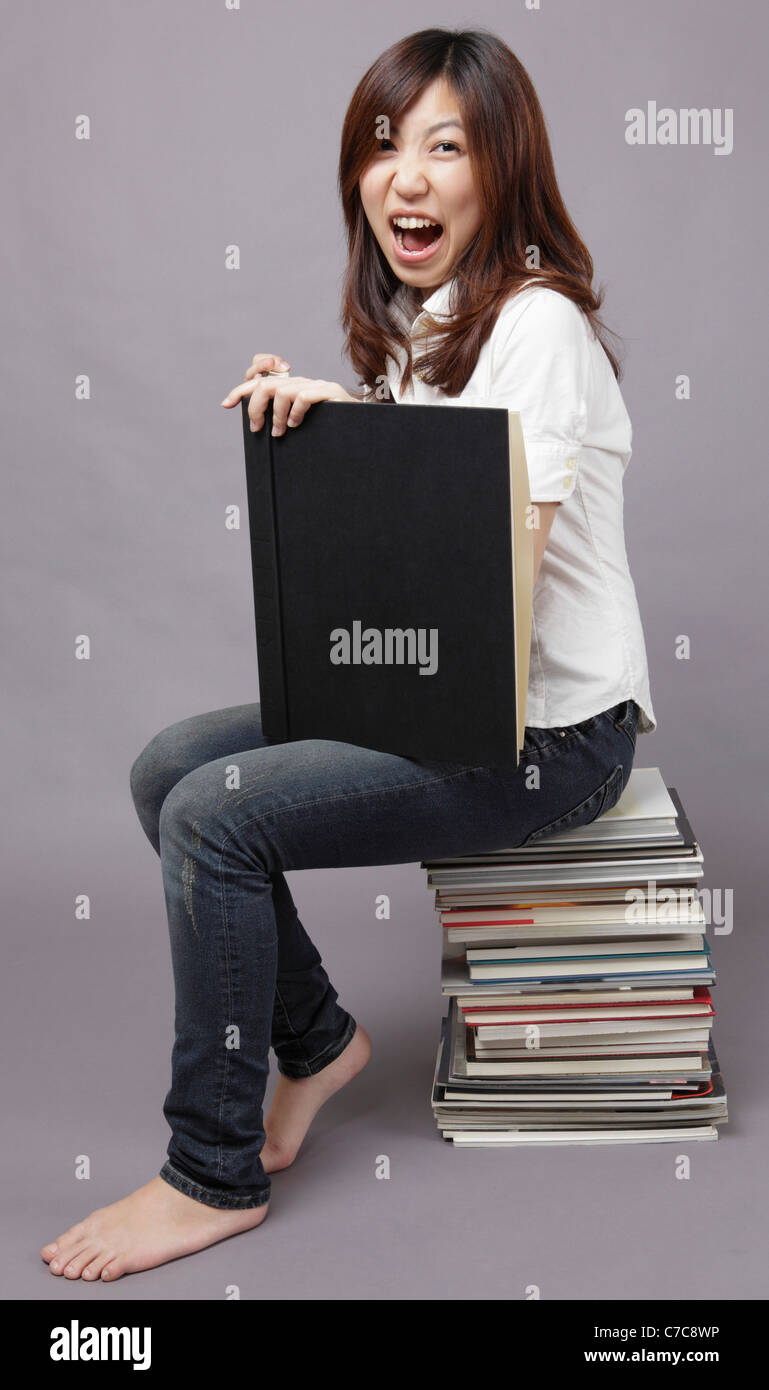 Girl sits on a pile of books Stock Photo - Alamy