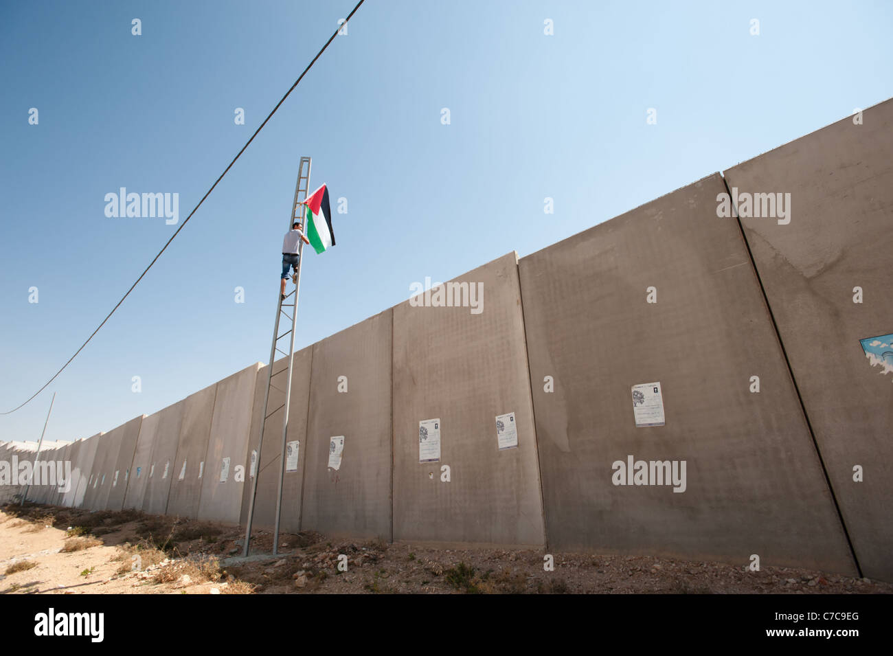 A youth raises a Palestinian flag on a tower near the wall between the ...