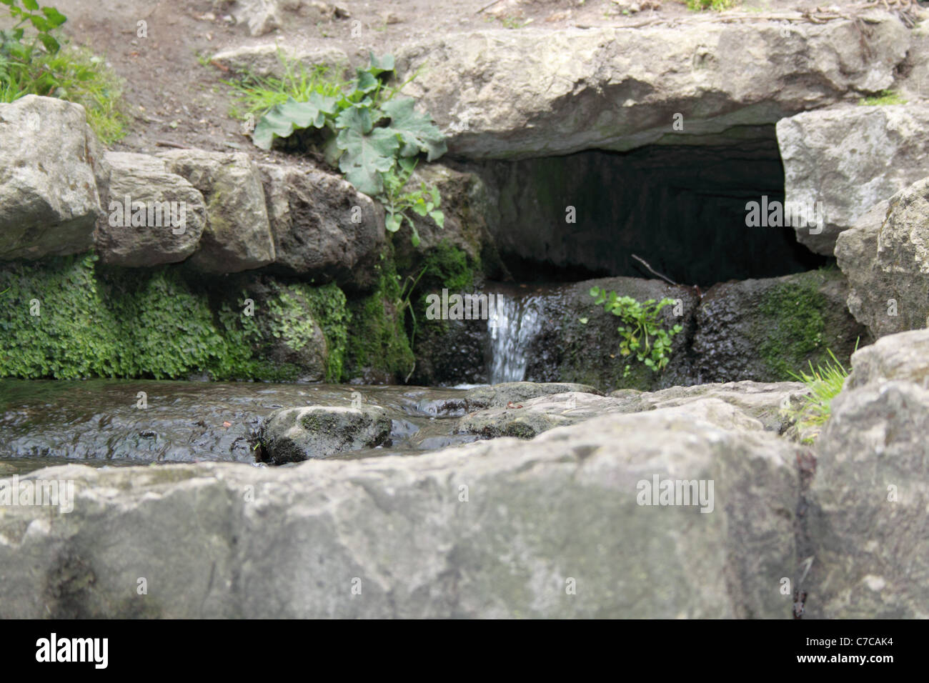 Top of the small waterfall flowing through rocks under a bridge in a ...