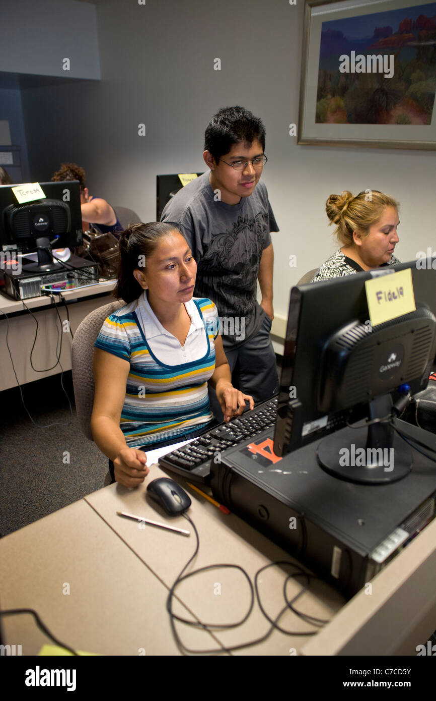 A young Hispanic teacher helps Hispanic students of different ages in a ...