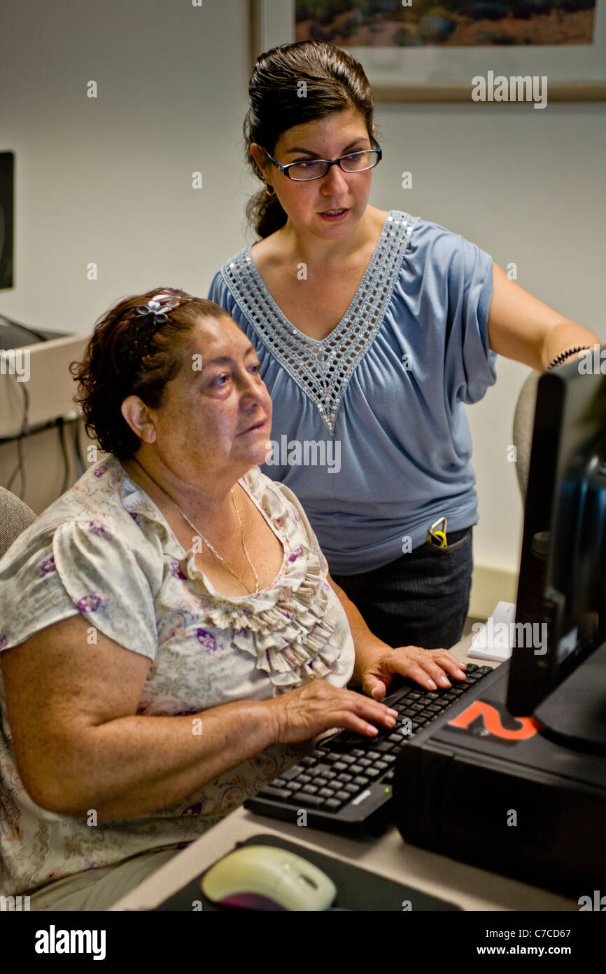 A young Hispanic teacher helps a senior Hispanic woman in a basic ...