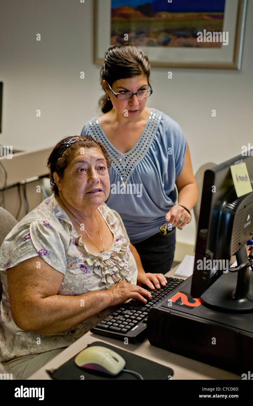 A young Hispanic teacher helps a senior Hispanic woman in a basic ...