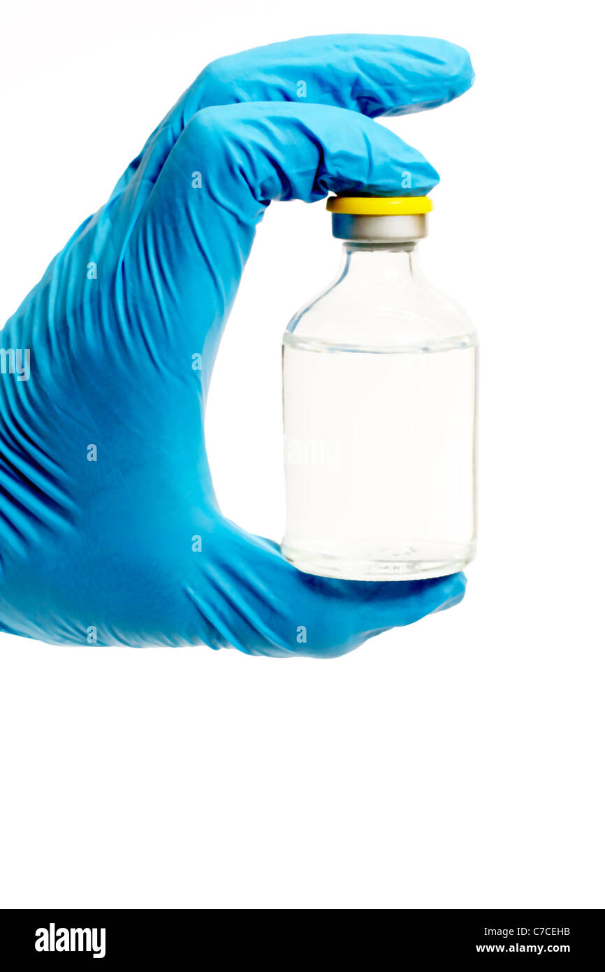 A gloved hand holding a vial between two fingers over a white ...