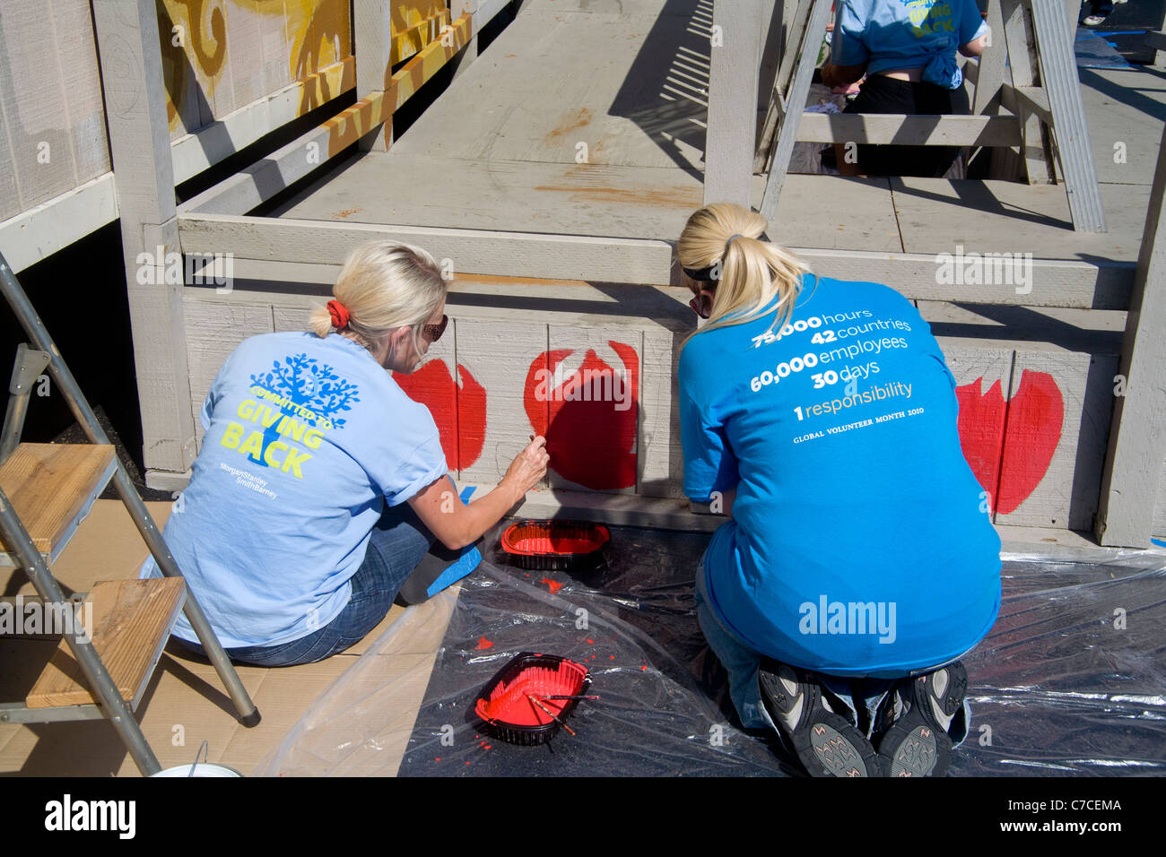 Two young women volunteers paint decorations on a city building during ...