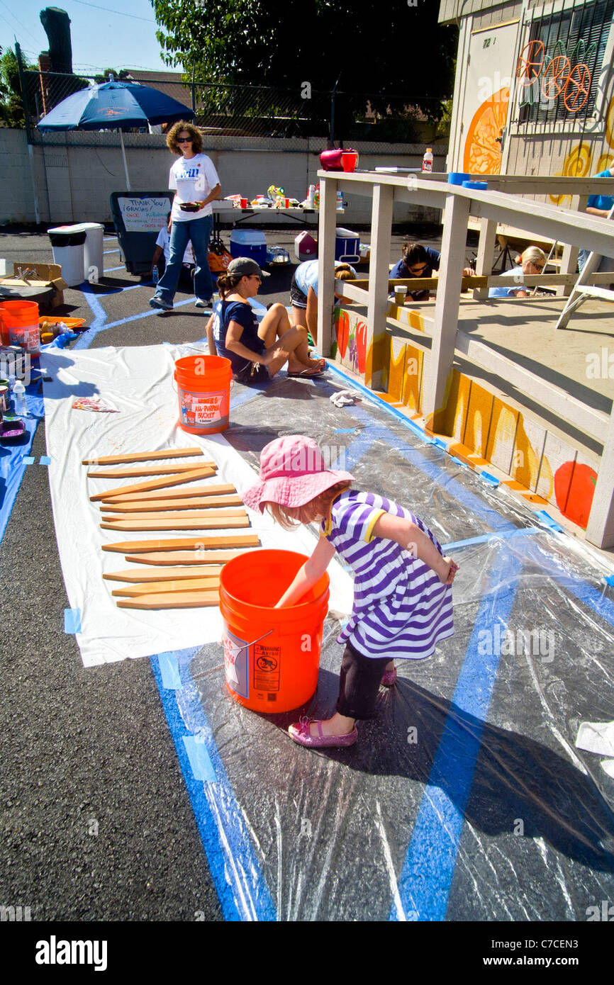 A young women volunteer and her daughters paint decorations on a city ...