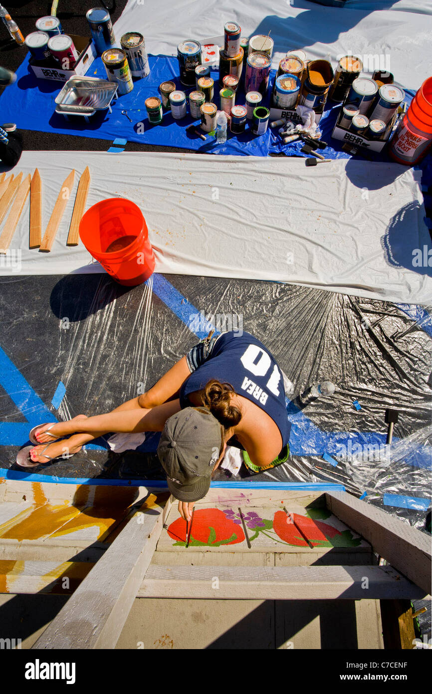 A young woman volunteer paints decorations on a city building during a ...