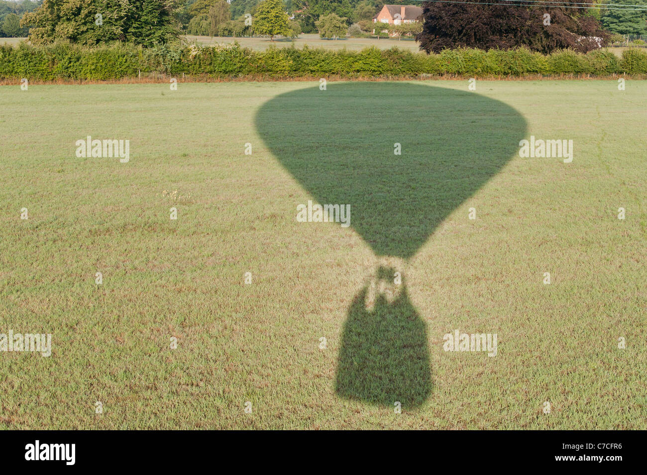 Shadow of hot air balloon on field, people visible in basket Stock ...