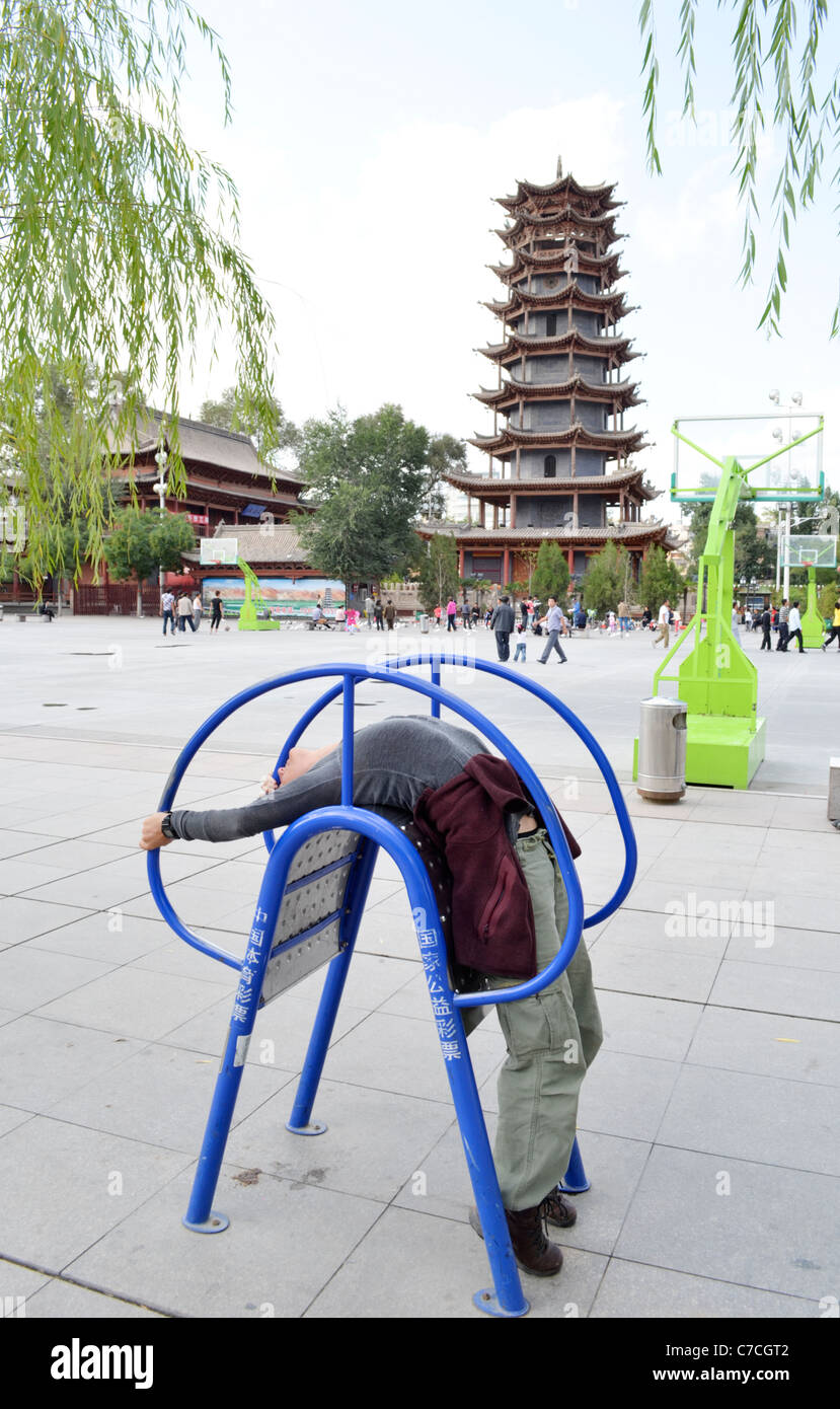 A woman stretches her back in a 'street gym' in Zhangye, Gansu, China ...