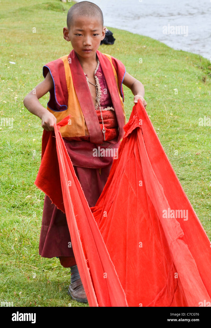 A young Tibetan Buddhist monk folds washing from his monastery after ...