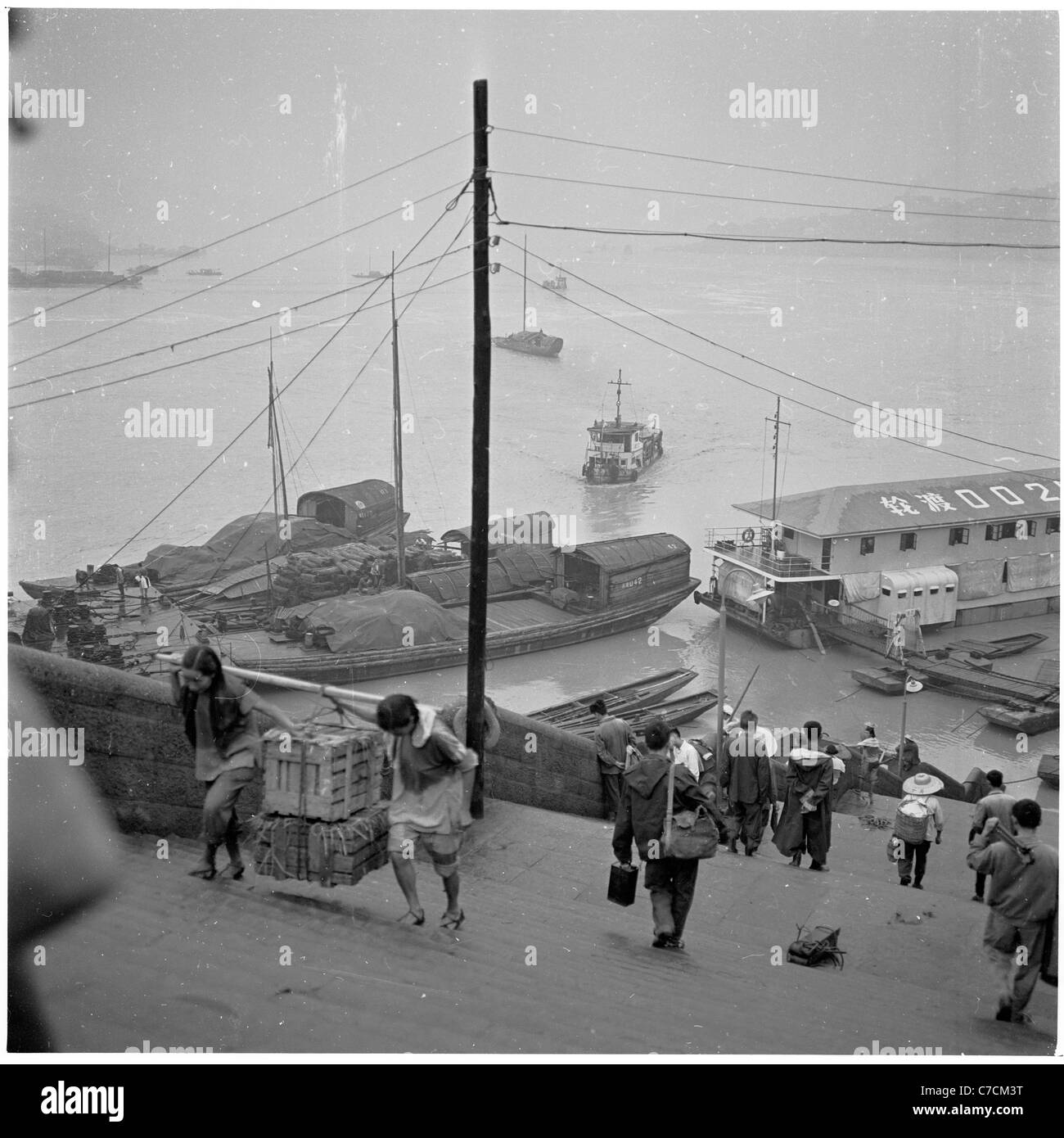 China, 1950s. Two young girls with baskets tied to pole which they ...