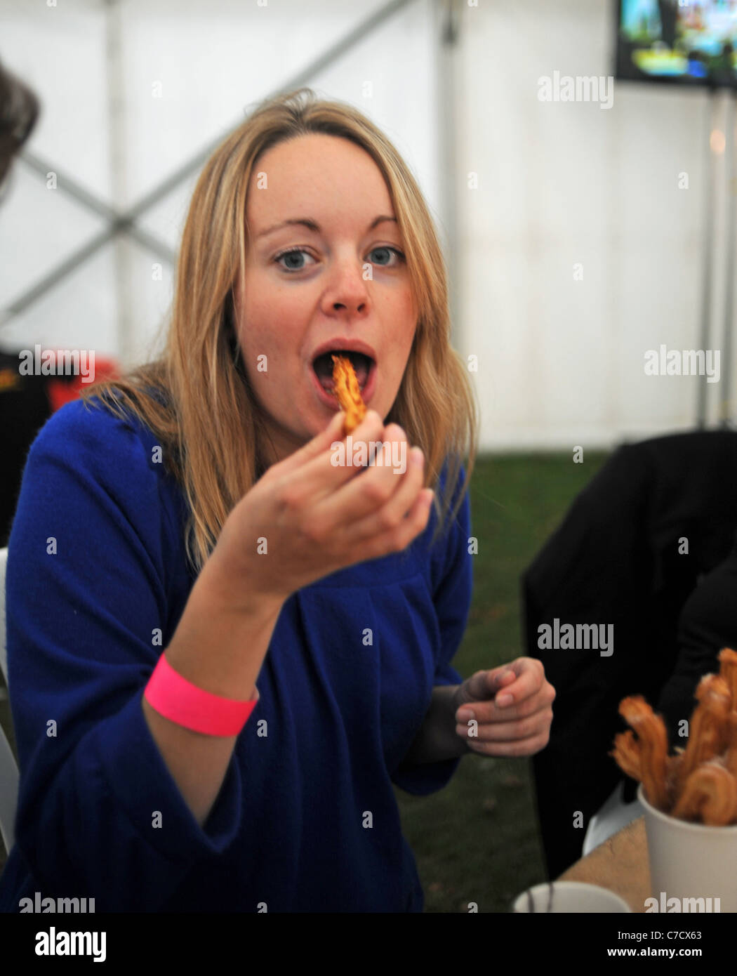 Young woman eating a sugar doughnut stick with chocolate sauce at the ...