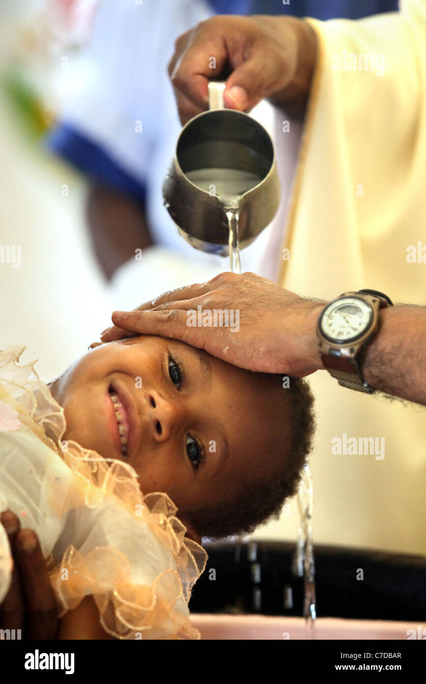 Baby in the arms of her mother is baptised (christened, called) by a ...