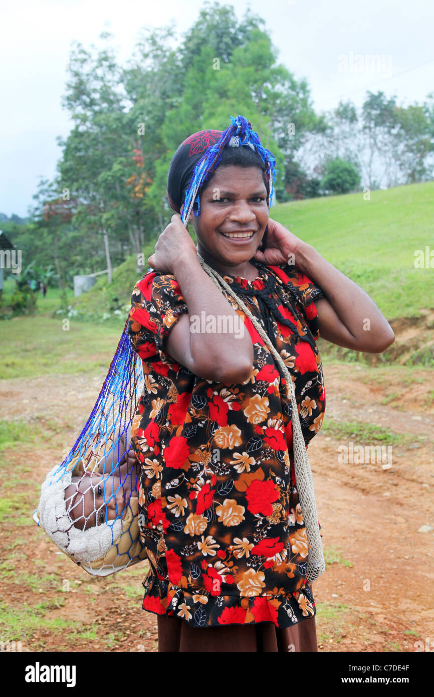 Mother carries her baby boy in a traditional woven bilum hanging from ...