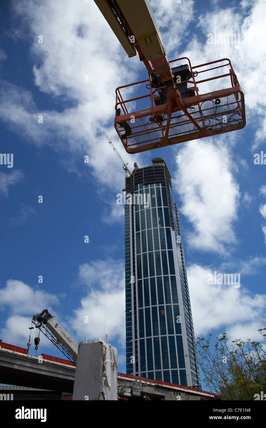 Blue skies and clouds above high-rise construction and lifter crane ...