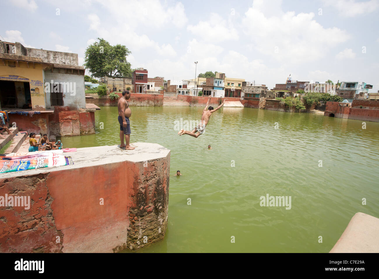 Group of men diving and swimming in pool of water in a village near ...