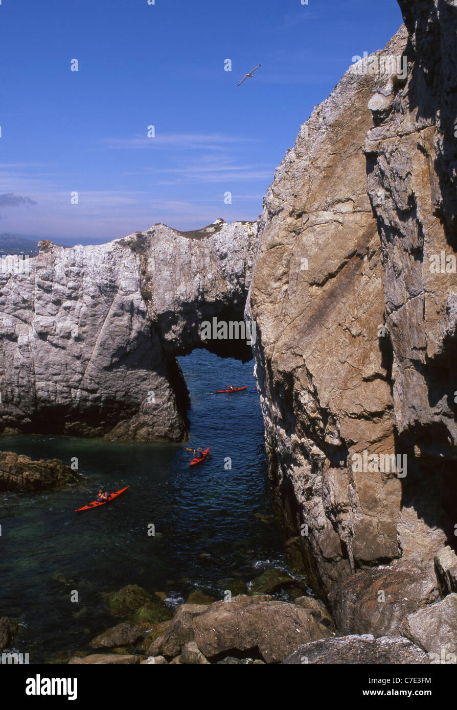 Sea kayakers passing beneath Bwa Gwyn Natural sea rock arch in cliffs ...