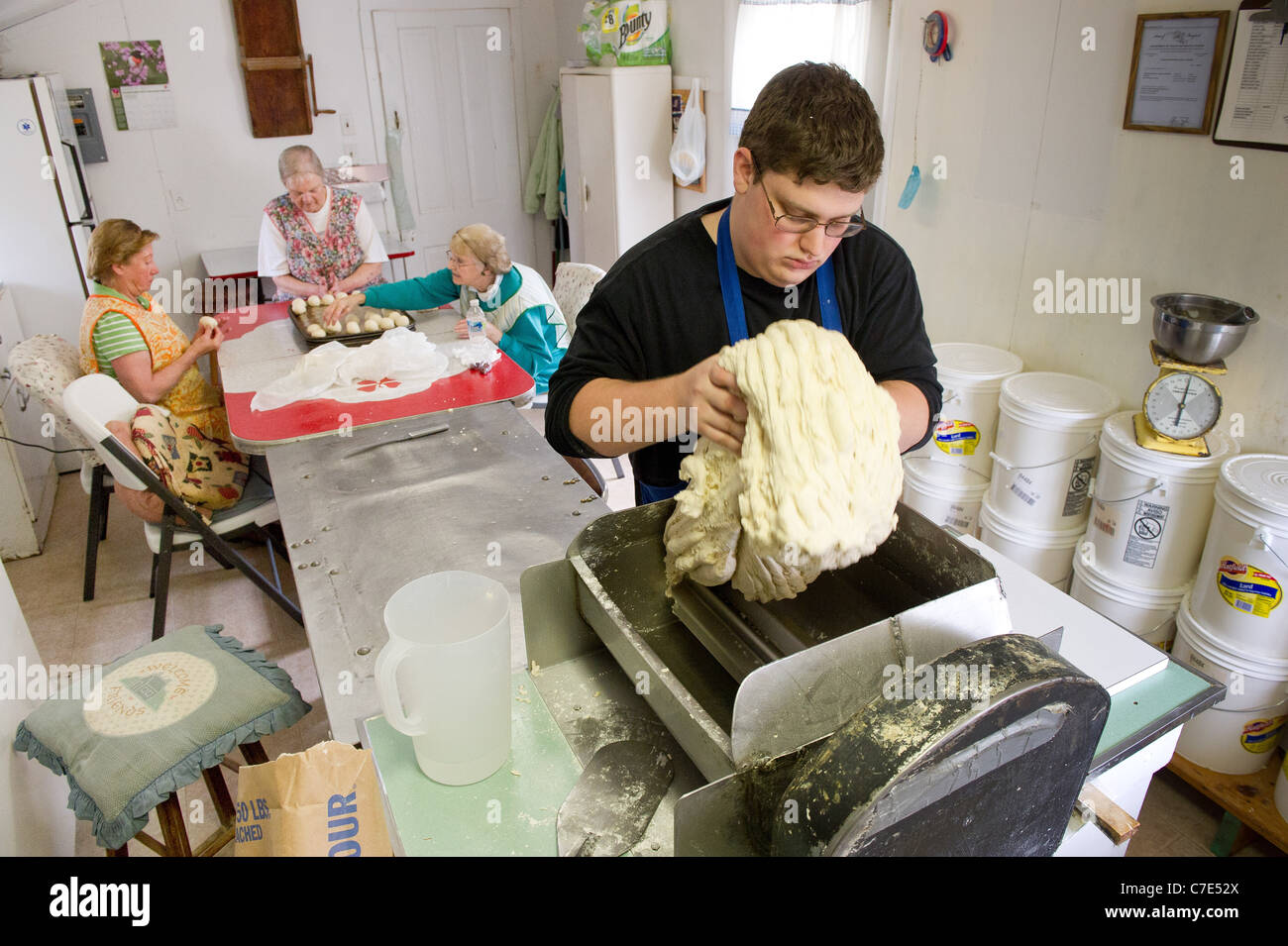 Woman and one man rolling dough in process of making beaten biscuits ...