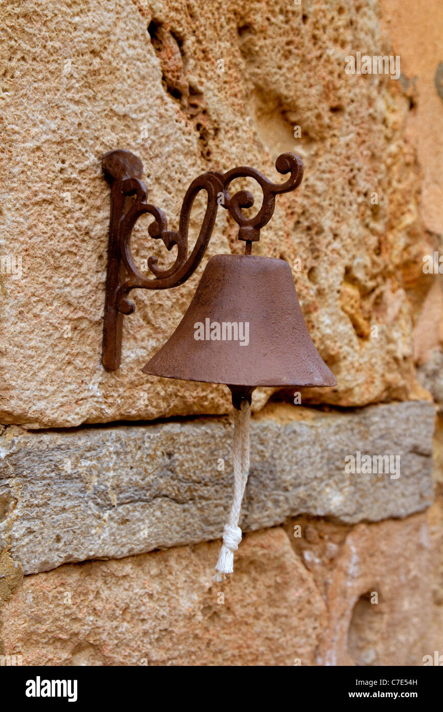 Aged rusty iron little bell hanging from stone wall in Majorca Stock ...