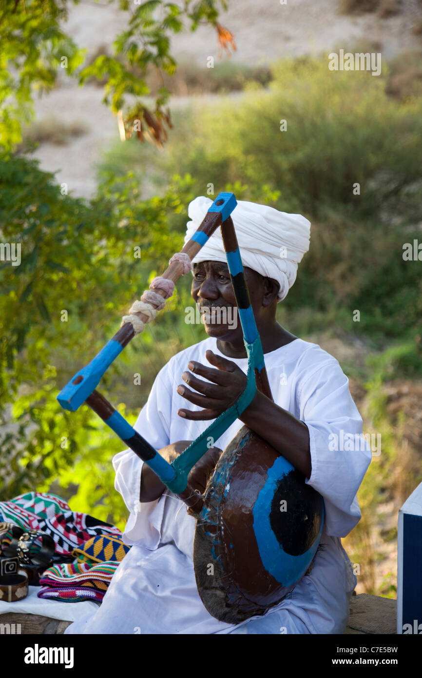 Man playing stringed musical instrument at the Philae Temple, Egypt ...