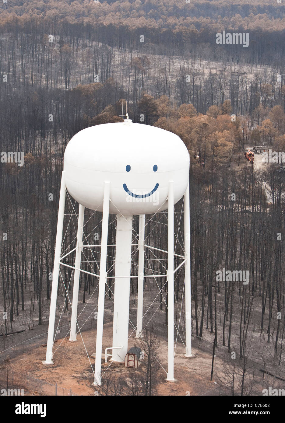 Aerial view of water tower with happy face painted on it looming over ...