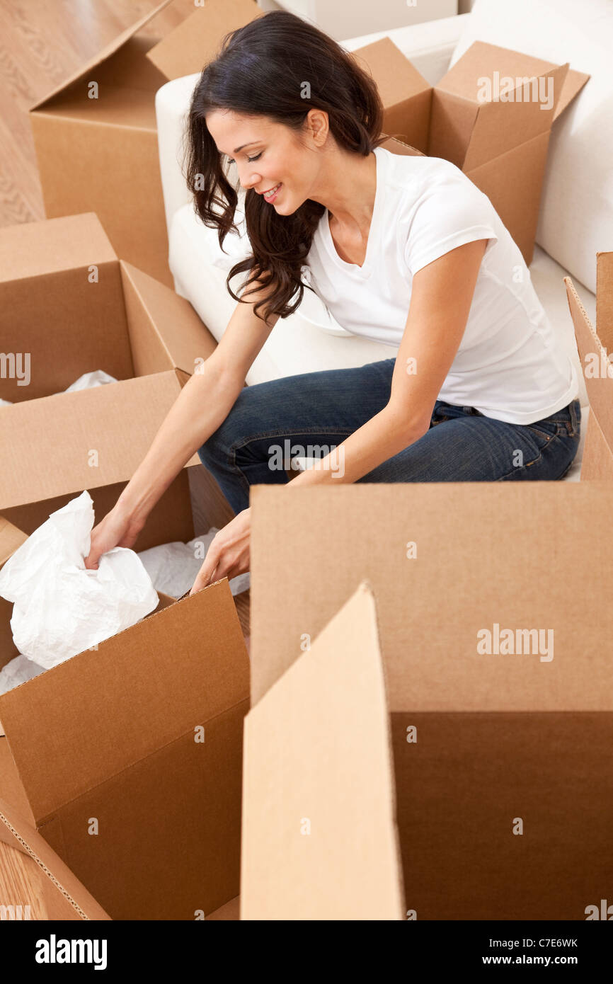 A beautiful single young woman unpacking boxes and moving into a new ...
