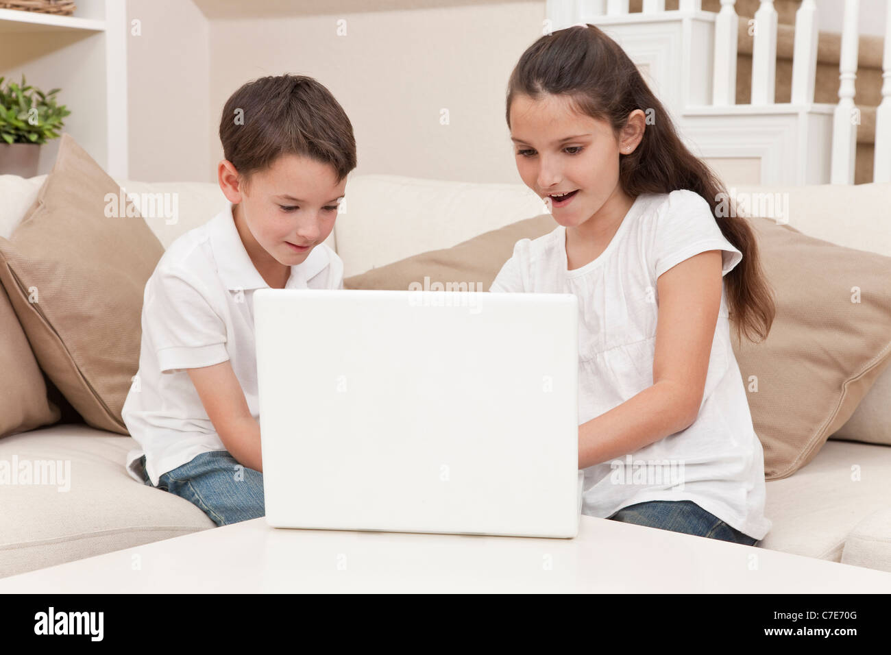Young boy & girl children using laptop computer on a sofa at home Stock ...