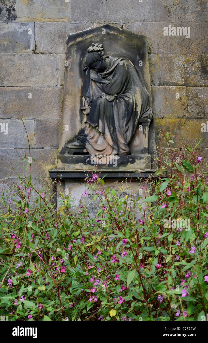 Memorial with the figure of a woman in mourning in an overgrown section ...