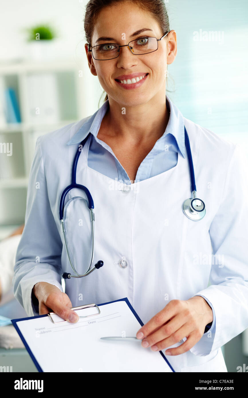 Portrait of confident female doctor with clipboard looking at camera ...