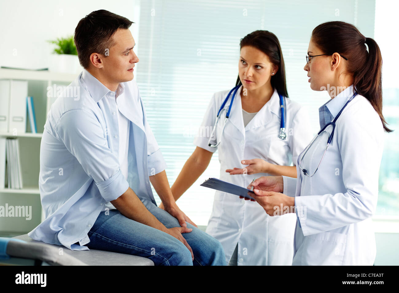 Portrait of confident female doctors consulting patient in hospital ...