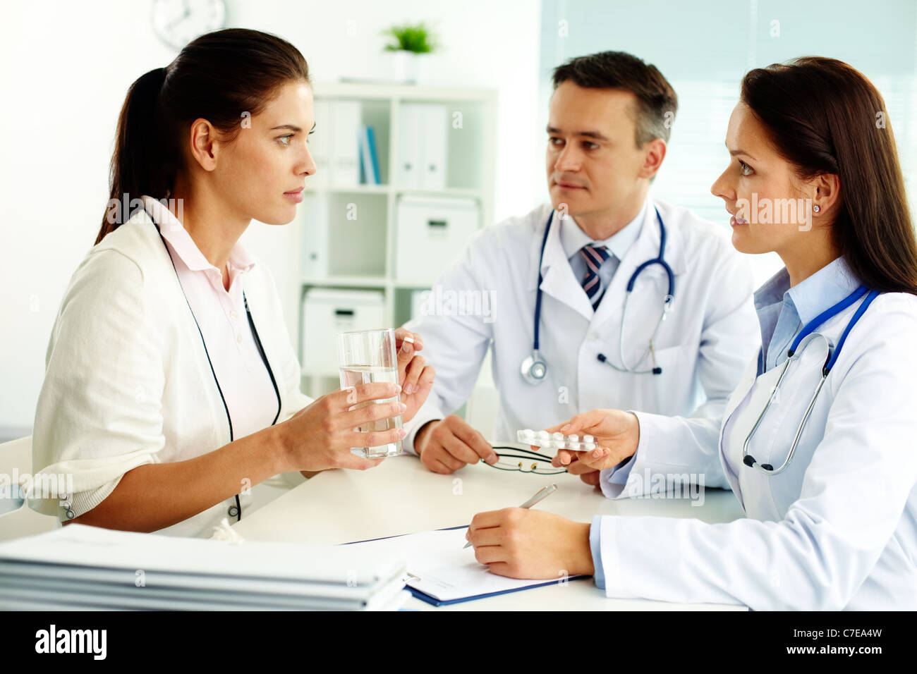 Portrait of confident practitioners prescribing tablets to patient in ...