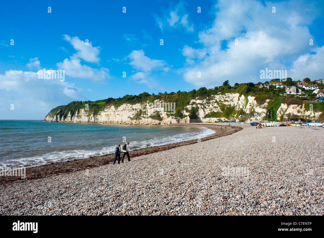 Man and woman walking along shingle beach at Beer Devon England Stock ...