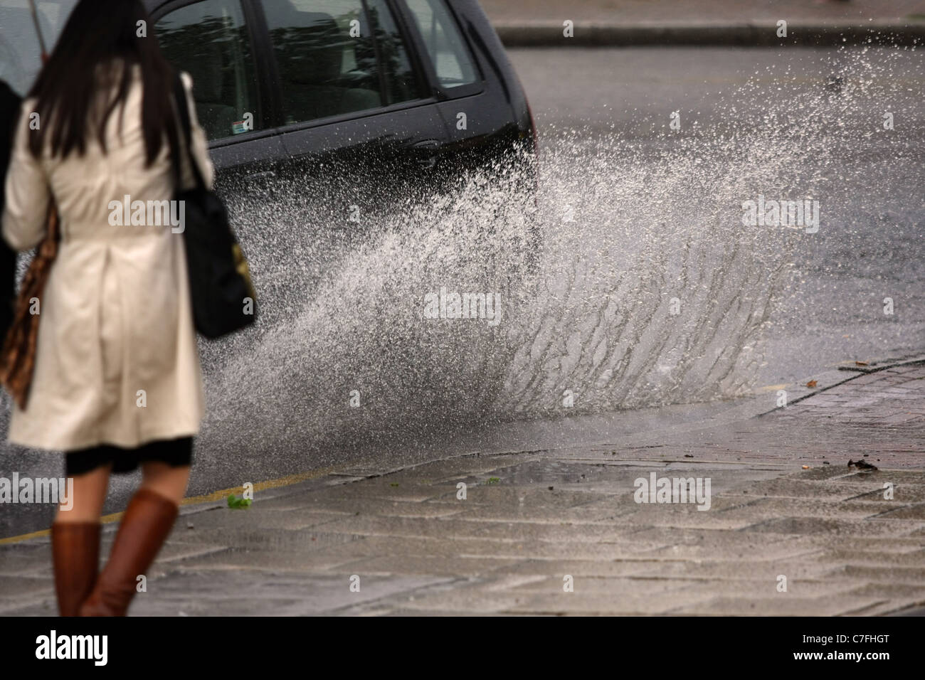 A vehicle driving through a puddle and a female passing by Stock Photo ...