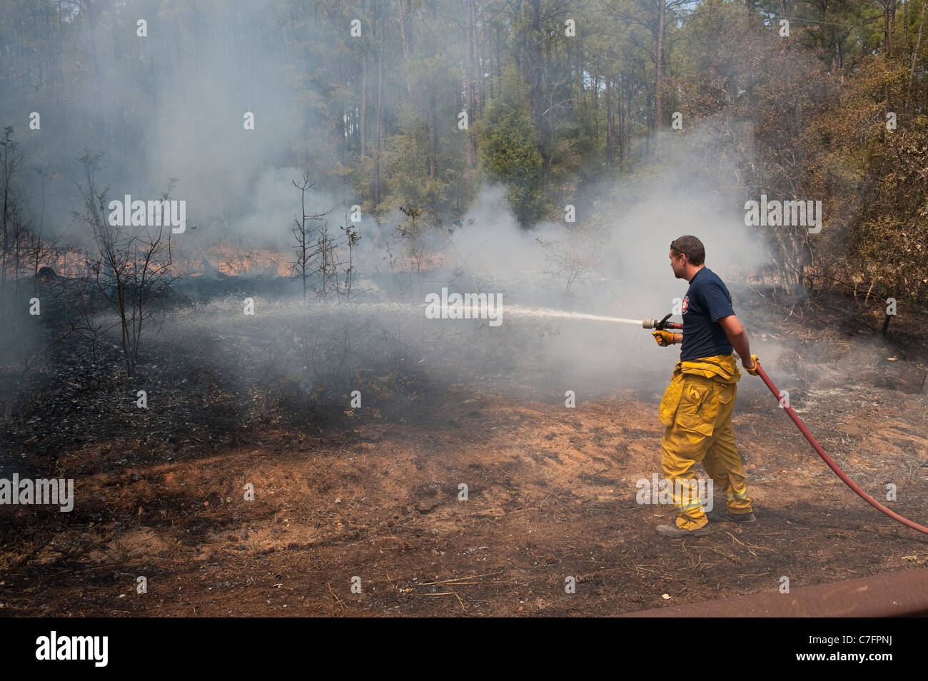Fire fighter uses a high-pressure water hose to battle an out-of ...