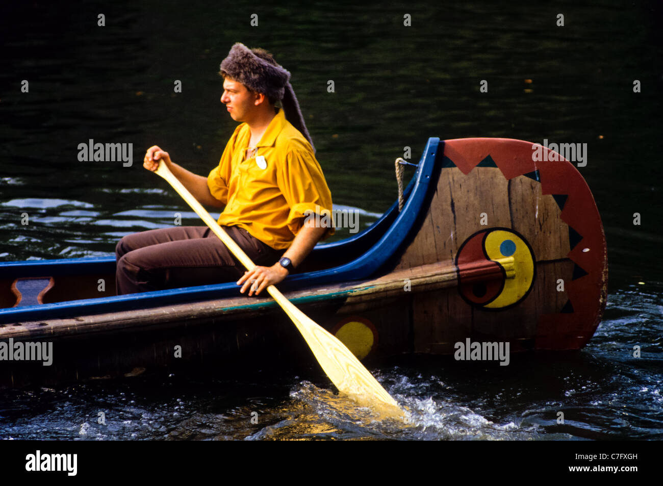 caucasian man with Indian hat paddling an Indian canoe in Disney World ...