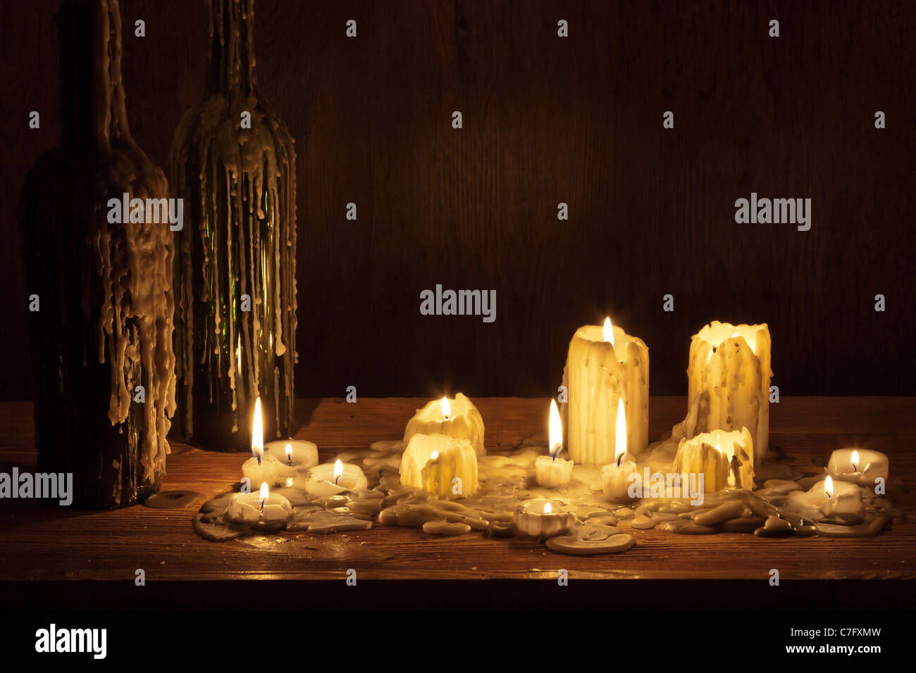 Melting candle in wooden shelf with bottle Stock Photo - Alamy