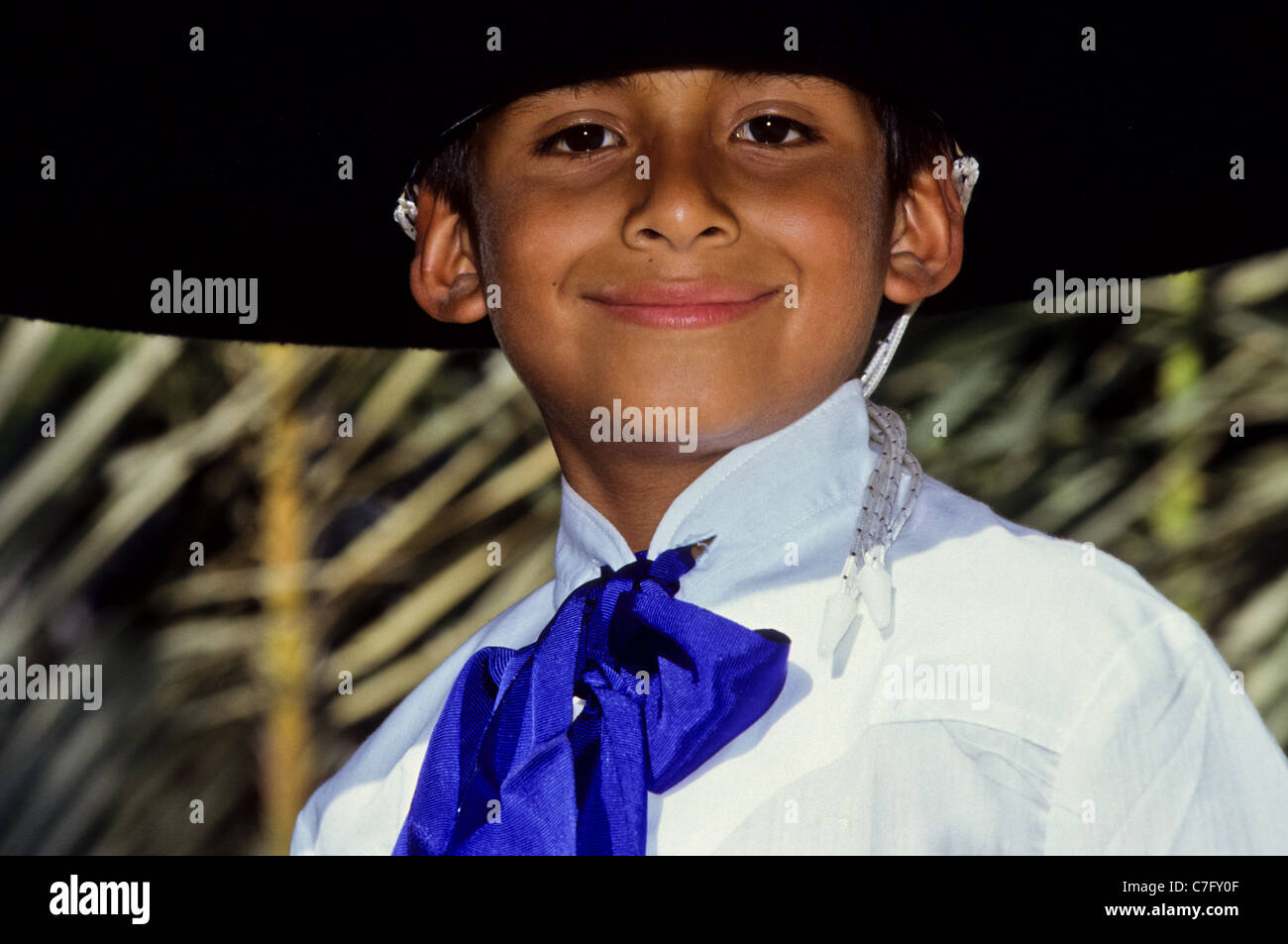 Portrait of a smiling Mexican boy with a big black hat and blue tie at ...