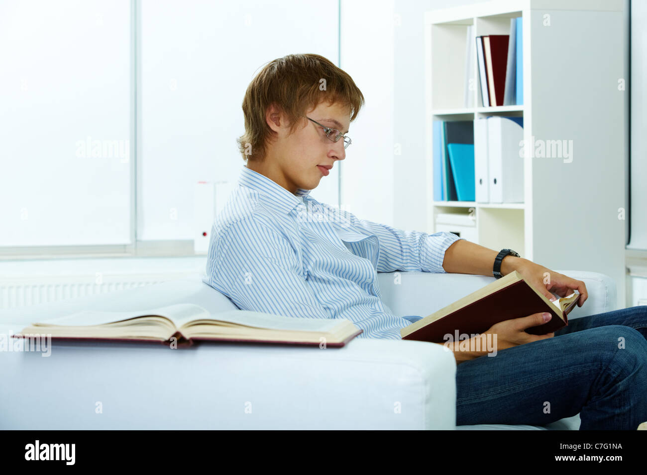 Image of serious student reading book indoors Stock Photo - Alamy