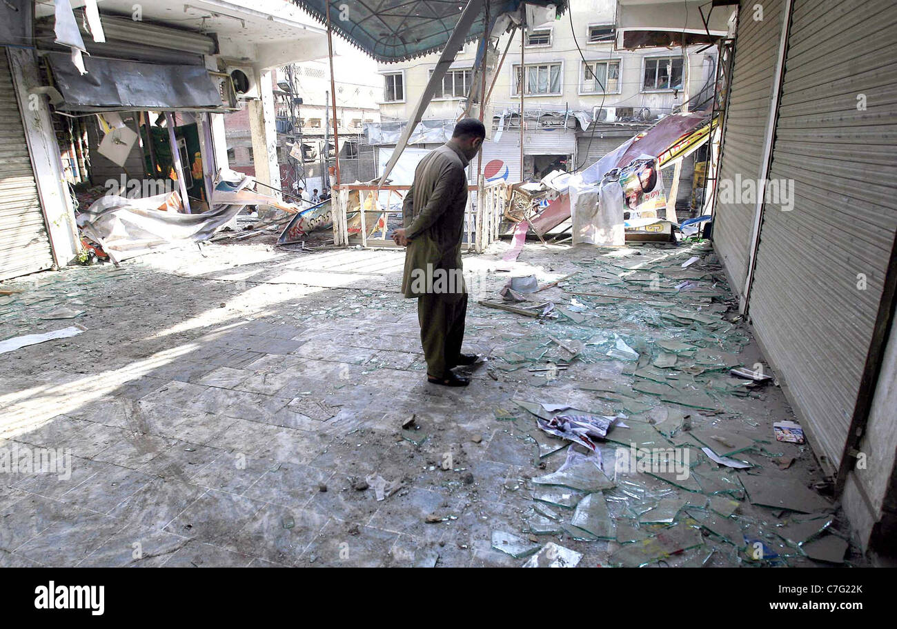 A man looks broken pieces of windowpanes in front of a damaged shop ...