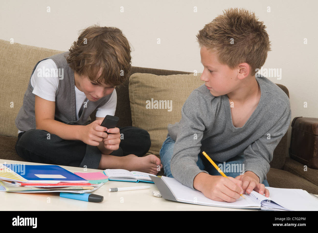 Two friends doing their homework in the livingroom. One of them is ...