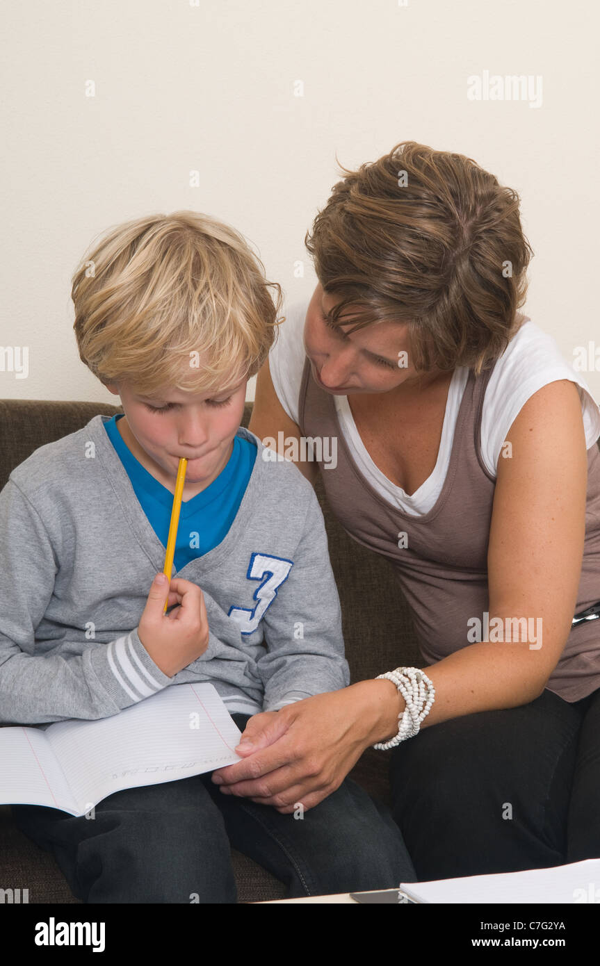 Boy is doing his homework in the livingroom while mother is helping him ...