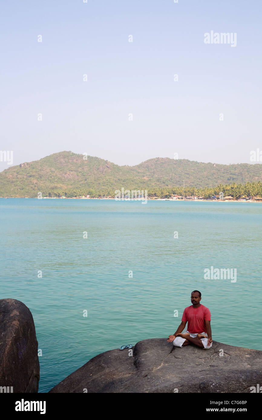 A man practices yoga on a rock overlooking a tropical ocean Stock Photo ...