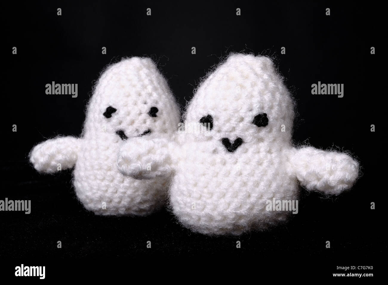 Two crochet toy ghosts made out of wool on a black background made for ...