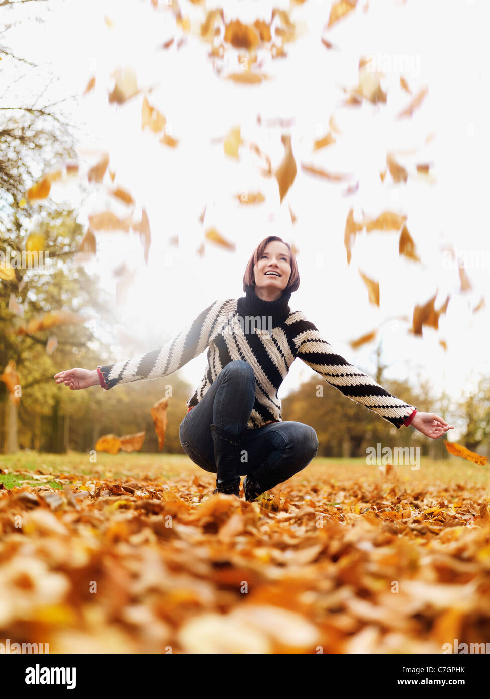 A woman looking up as autumn leaves fall Stock Photo - Alamy