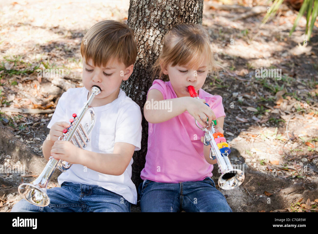 A boy and a girl sitting and playing toy musical instruments Stock ...