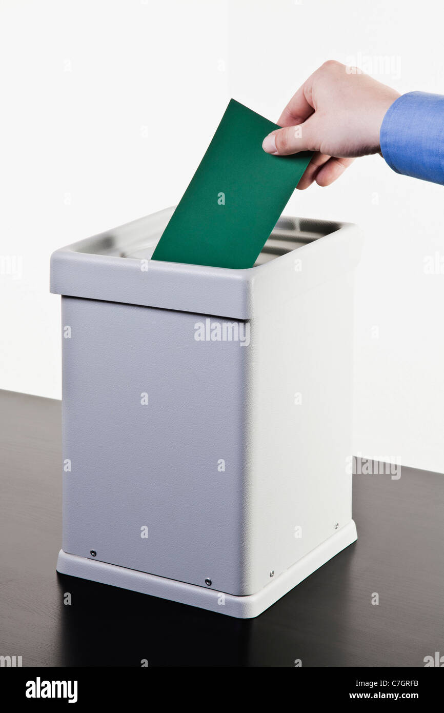 A man putting a blank green ballot into a ballot box, close-up hands ...