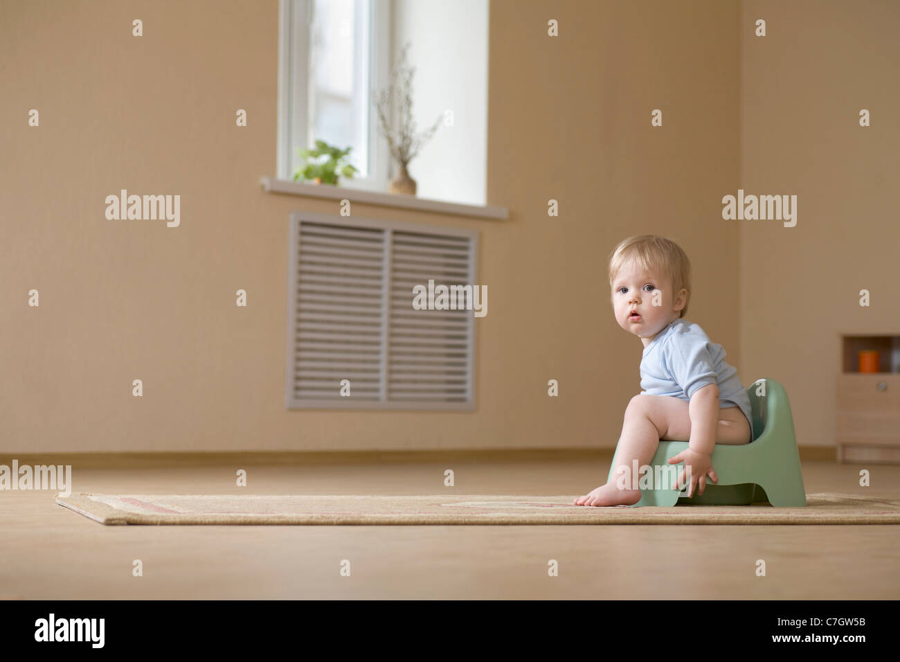 A toddler sitting on a potty chair, looking at camera Stock Photo - Alamy