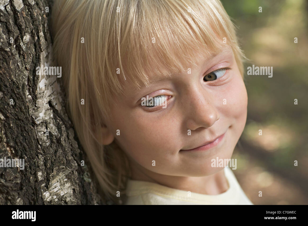 A young girl leaning against a tree, sideways glance Stock Photo - Alamy
