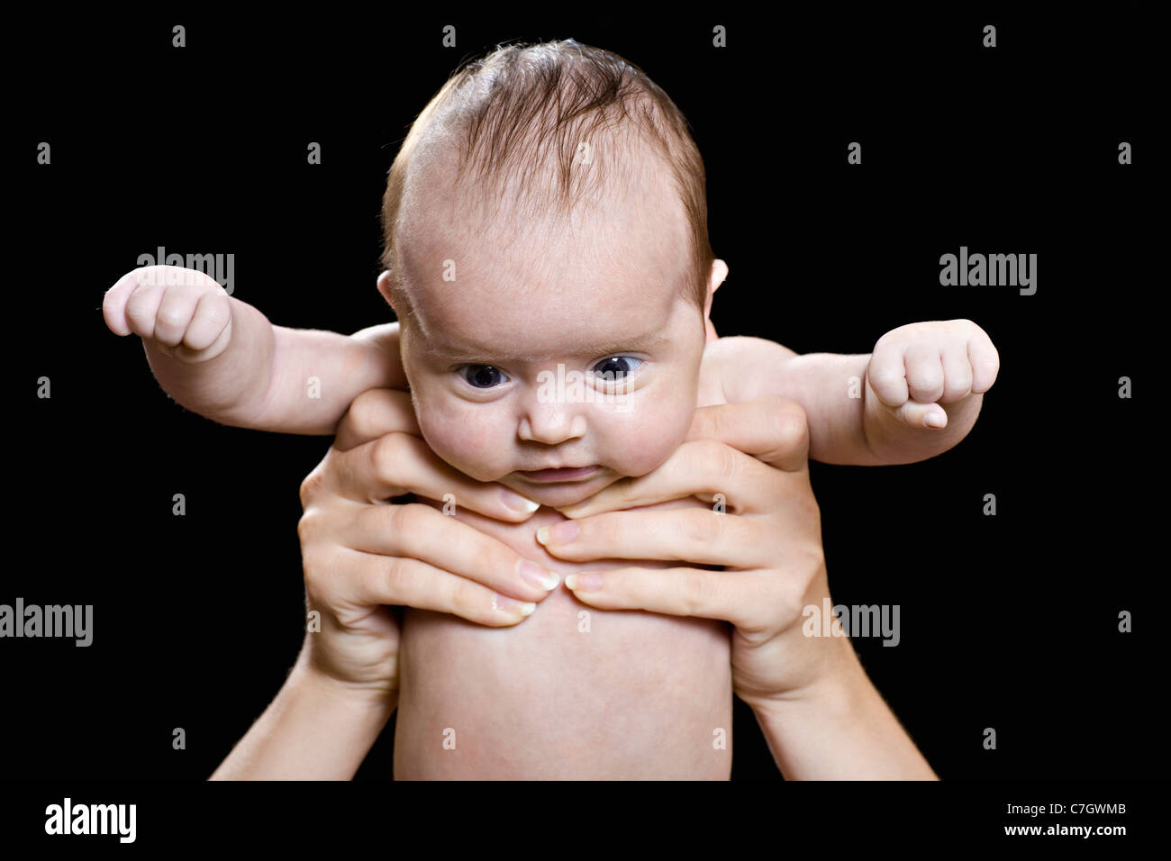 A baby held aloft staring down Stock Photo - Alamy