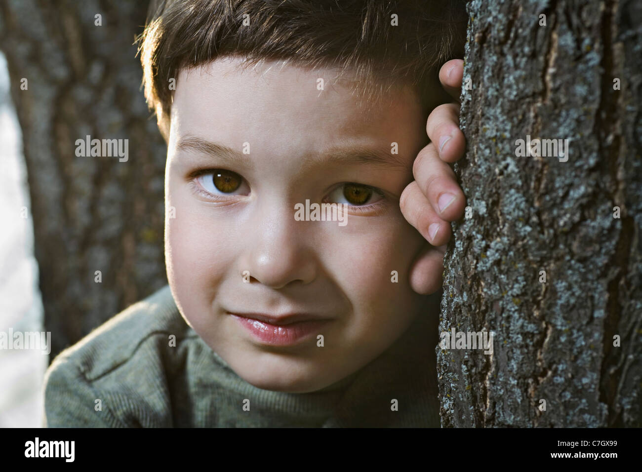 A young tired boy leaning on a tree Stock Photo - Alamy