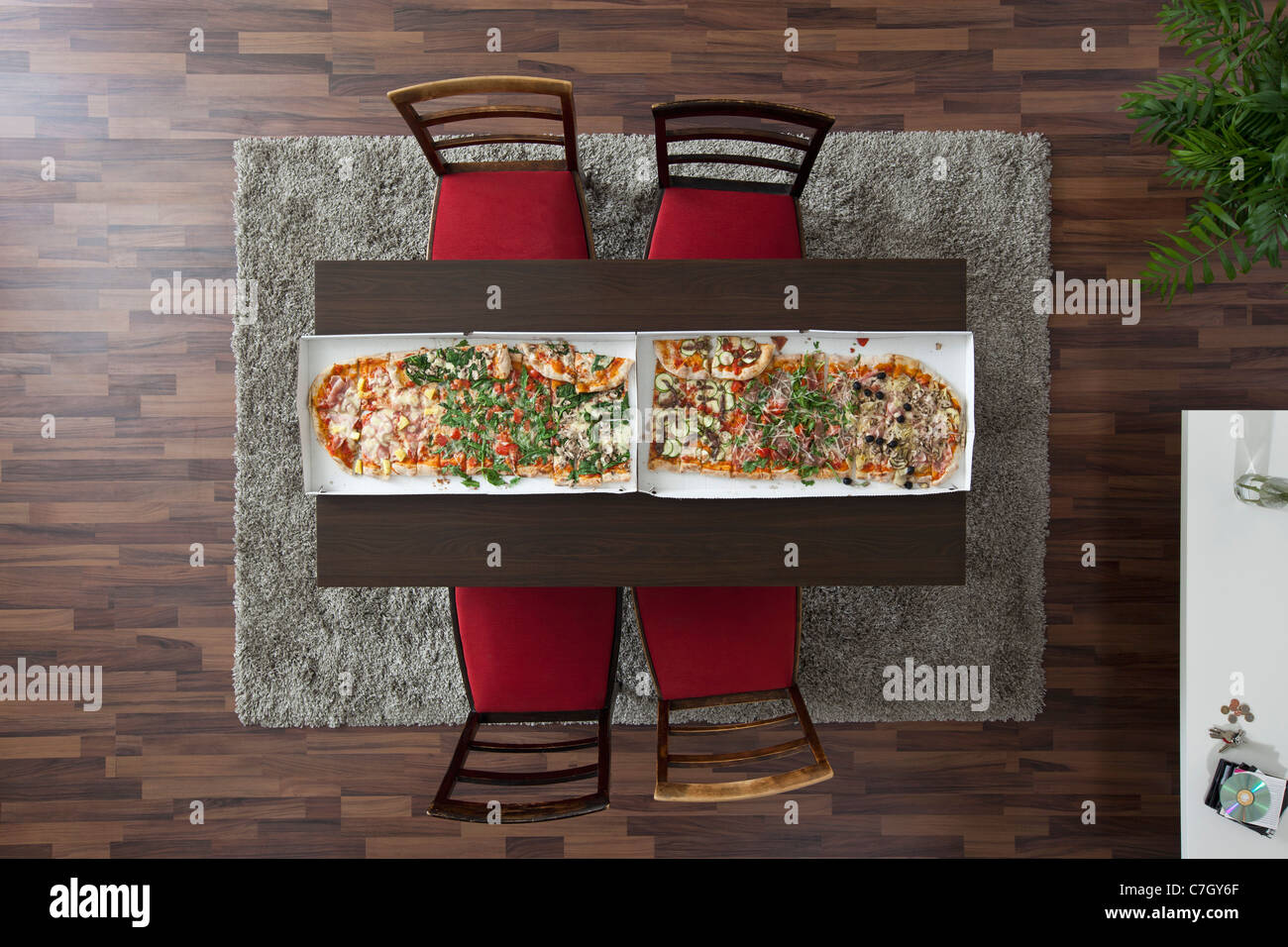 Two large pizzas side by side running the length of a table, overhead ...